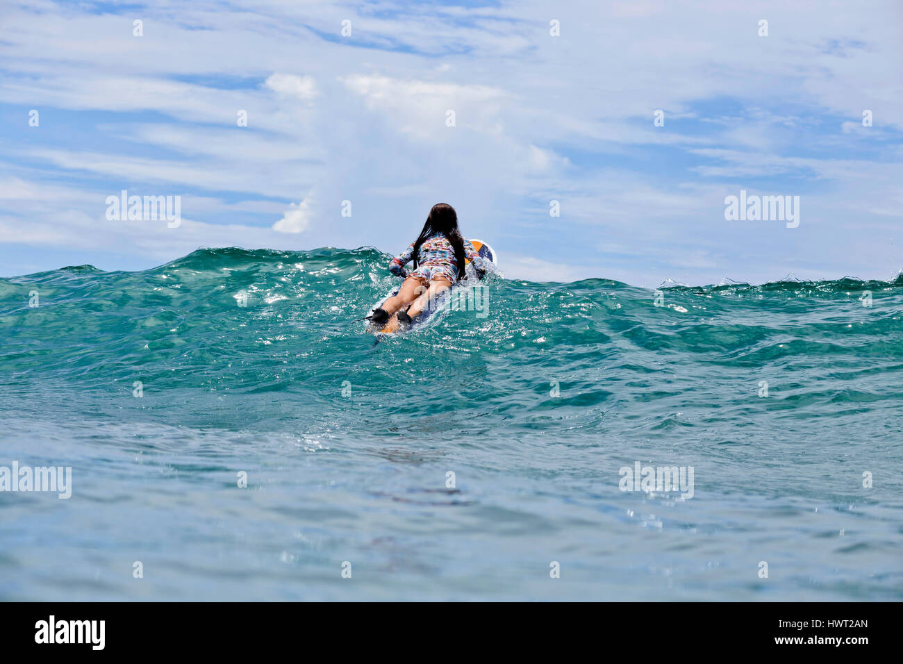Rear view of woman surfboarding on wave in sea Stock Photo - Alamy
