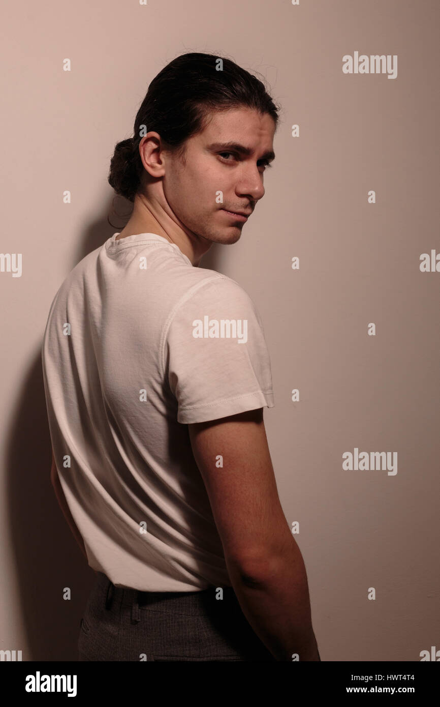 Handsome guy in white clothes turns and peeks out from behind Stock ...