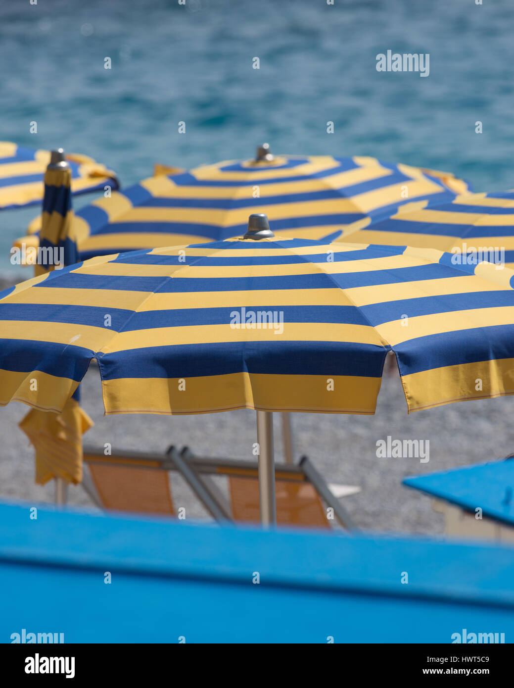 Yellow and blue beach umbrellas on the mediterranean beach of Noli ...