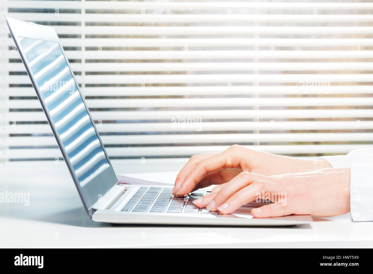 Hands typing on laptop keyboard next to the window Stock Photo - Alamy