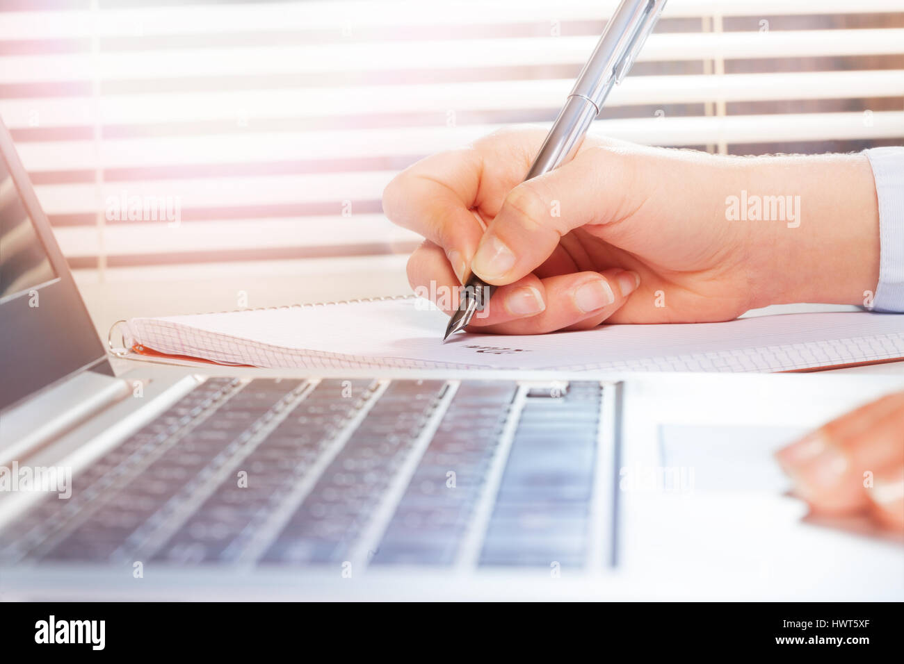 Hands using laptop and making notes on notepad Stock Photo - Alamy