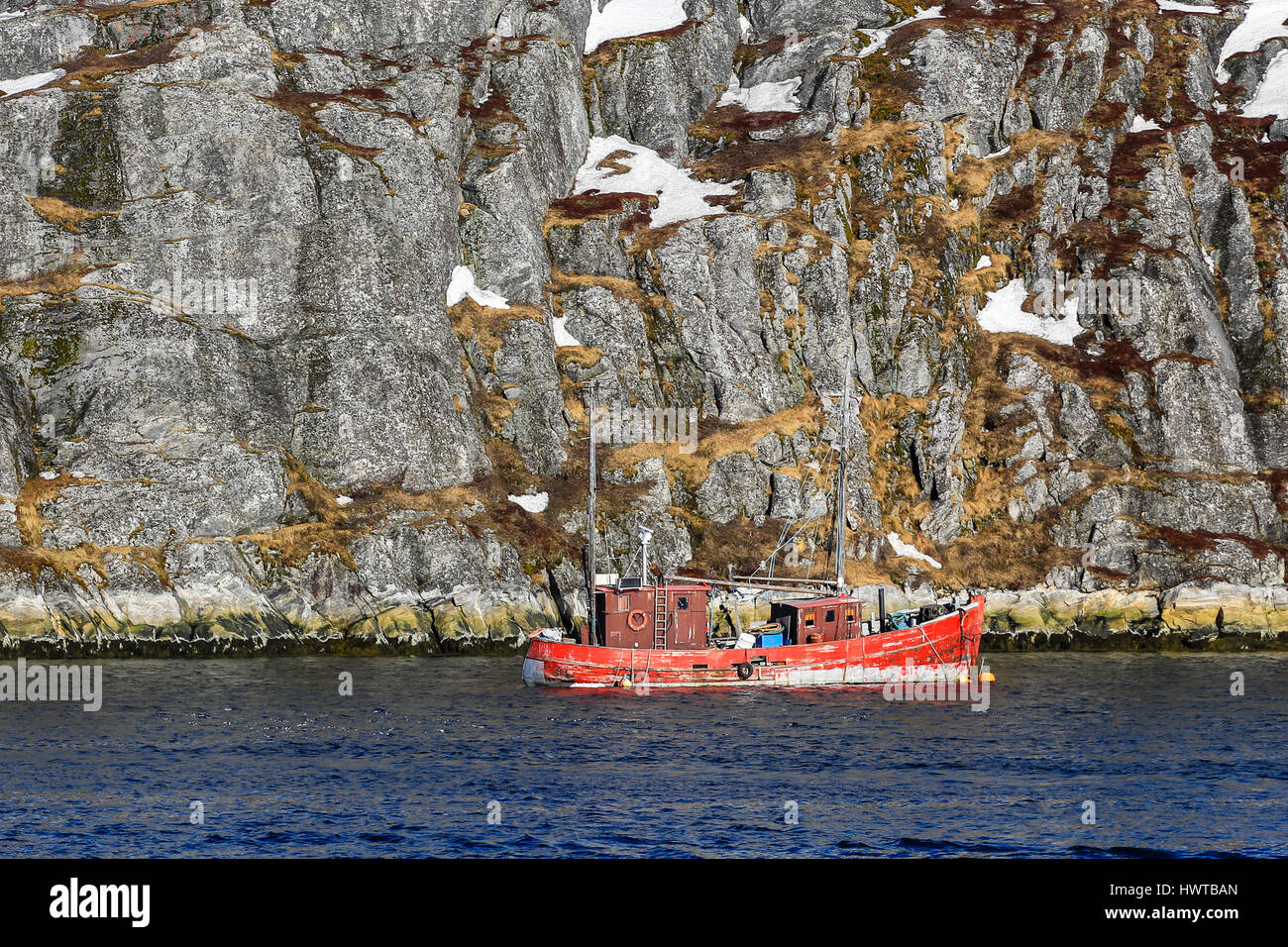 Lone fishing boat floating near steep cliff, Nuuk fjord, Greenland ...