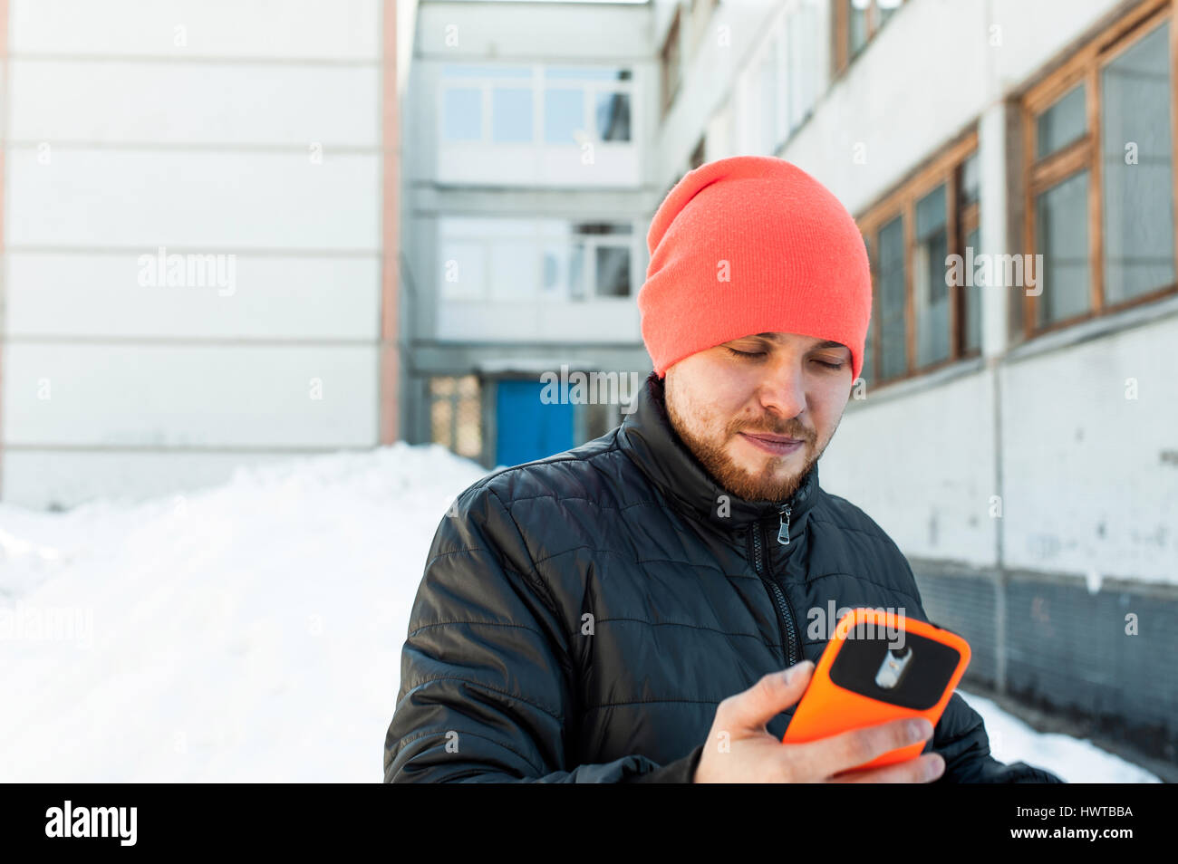 man Looks at the smartphone screen. guy with beard, dressed in an ...