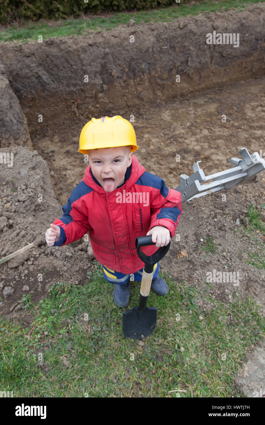 Little boy with a spade helps parents during the construction of the ...