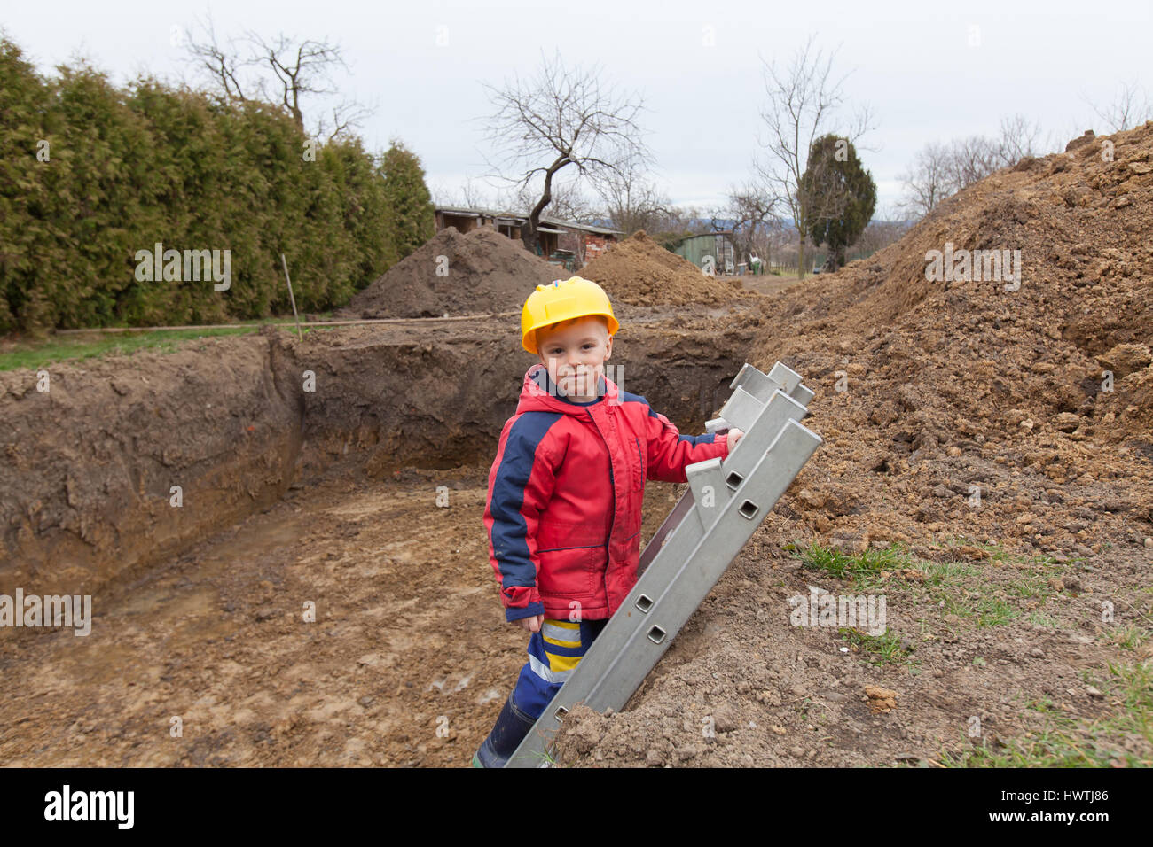 Little boy with a spade helps parents during the construction of the ...
