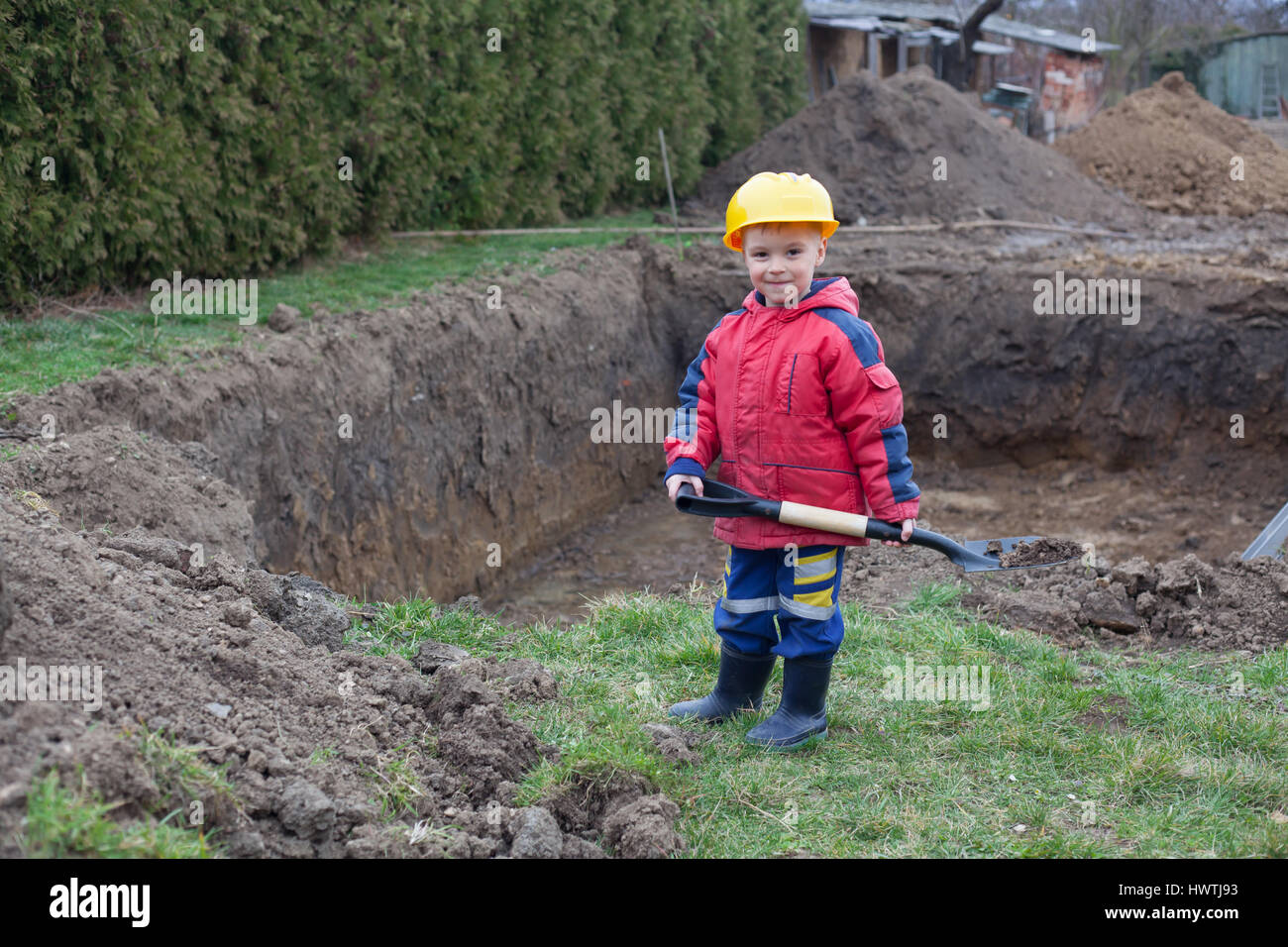 Little boy with a spade helps parents during the construction of the ...
