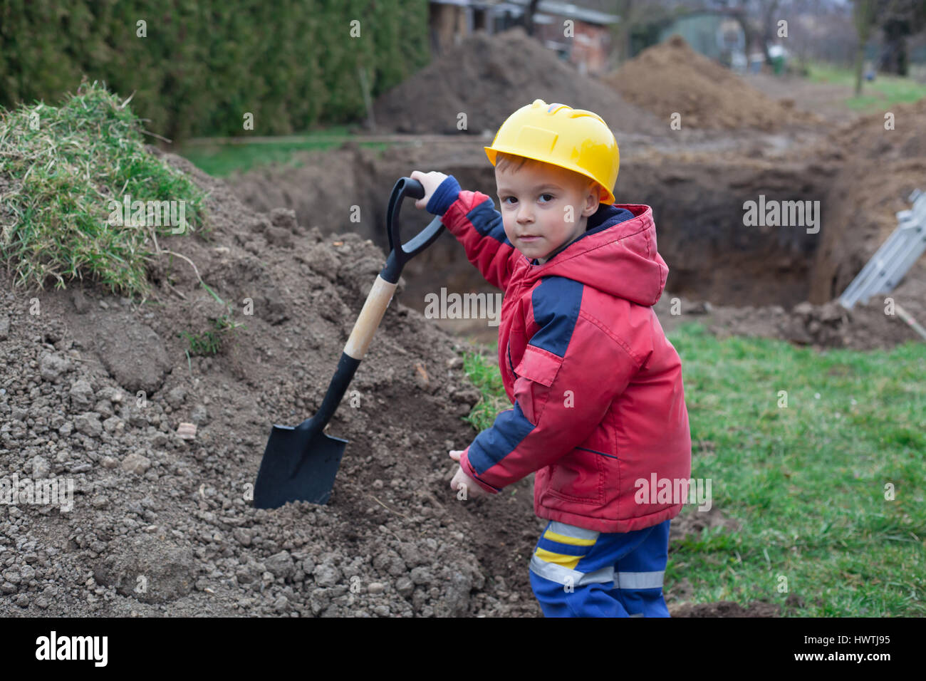 Little boy with a spade helps parents during the construction of the ...