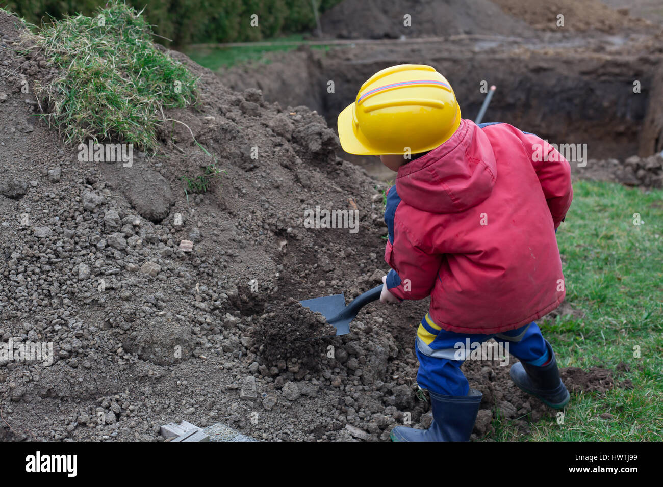Little boy with a spade helps parents during the construction of the ...