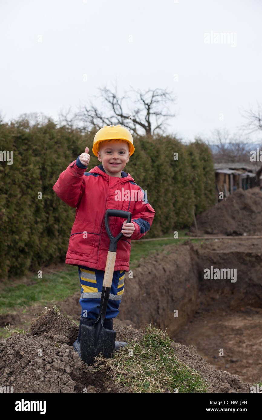 Little boy with a spade helps parents during the construction of the ...