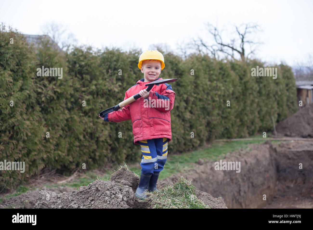 Little boy with a spade helps parents during the construction of the ...