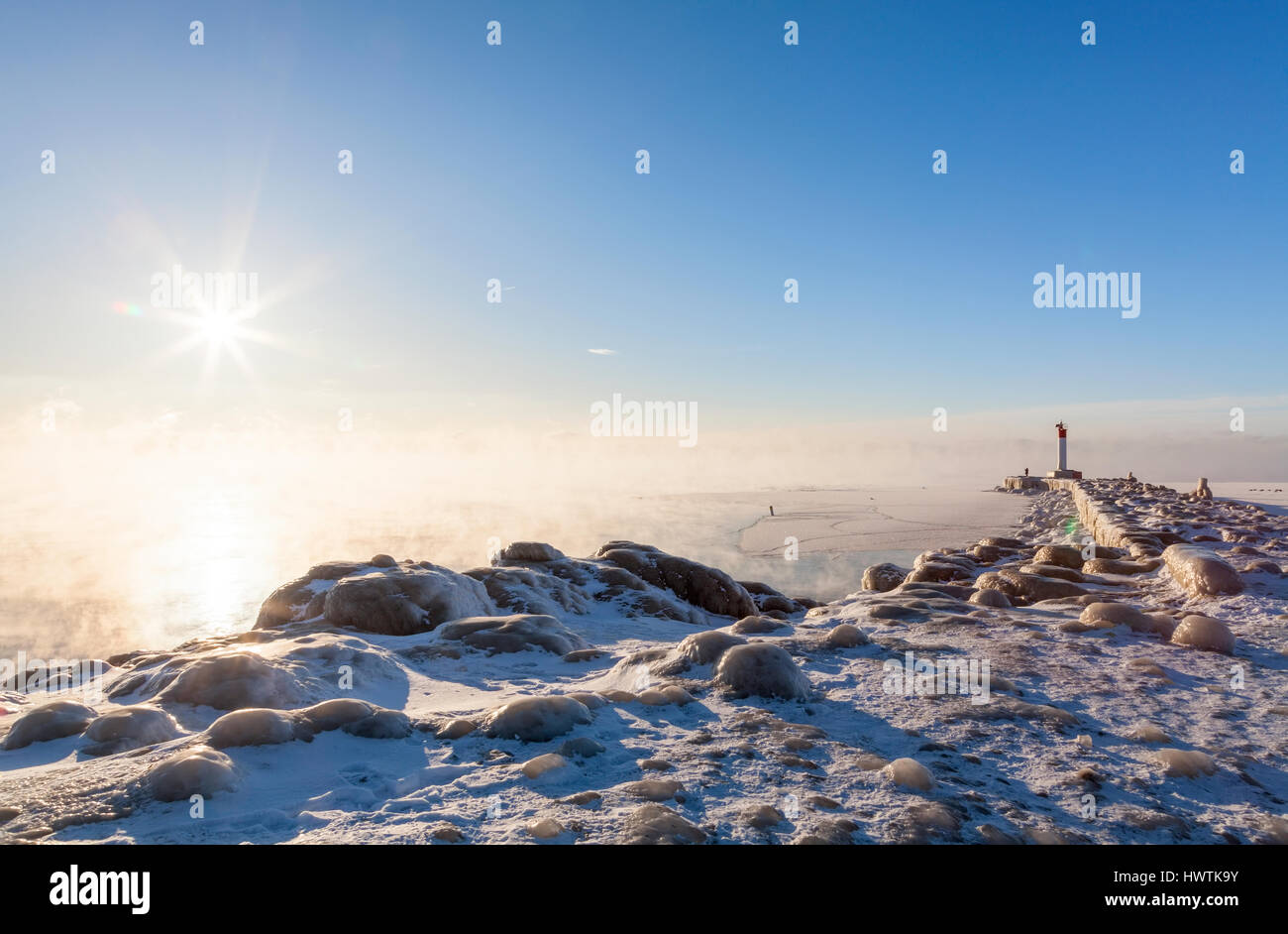 An ice covered pier and lighthouse on a very cold foggy morning on Lake ...