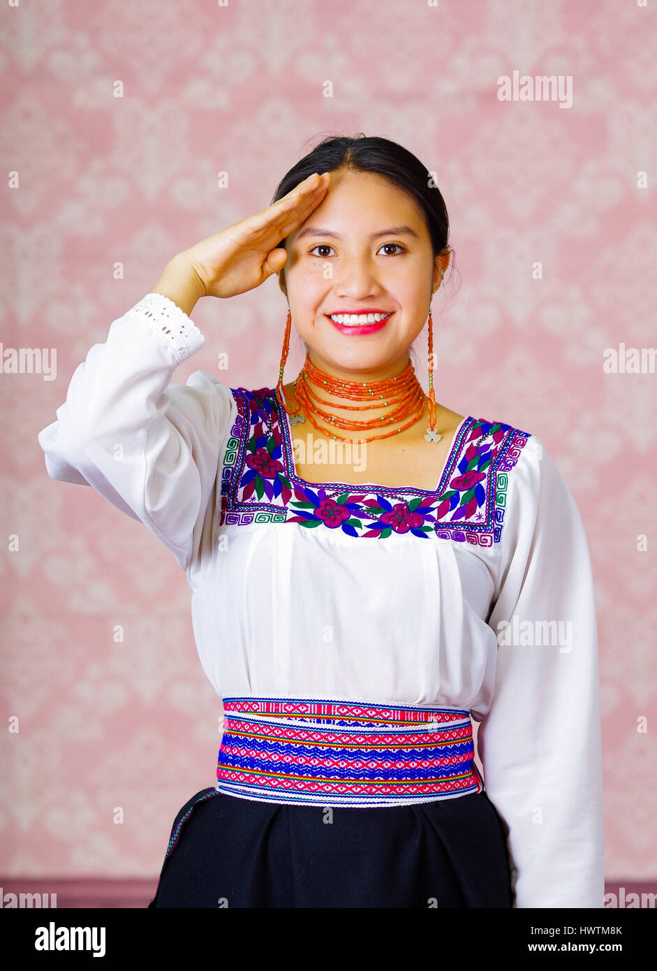 Young woman wearing traditional andean dress, facing camera doing sign ...