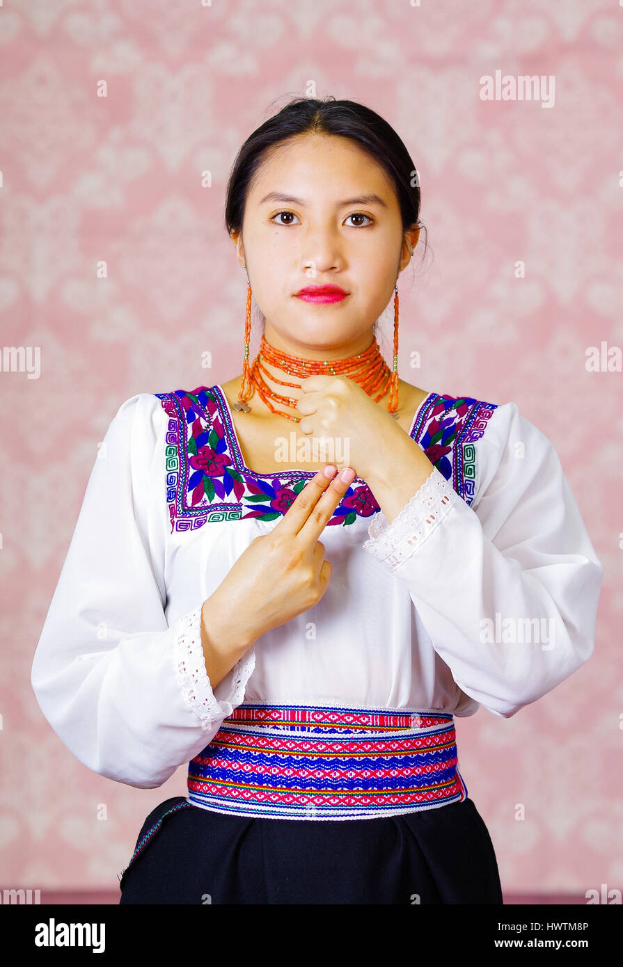 Young woman wearing traditional andean dress, facing camera doing sign ...