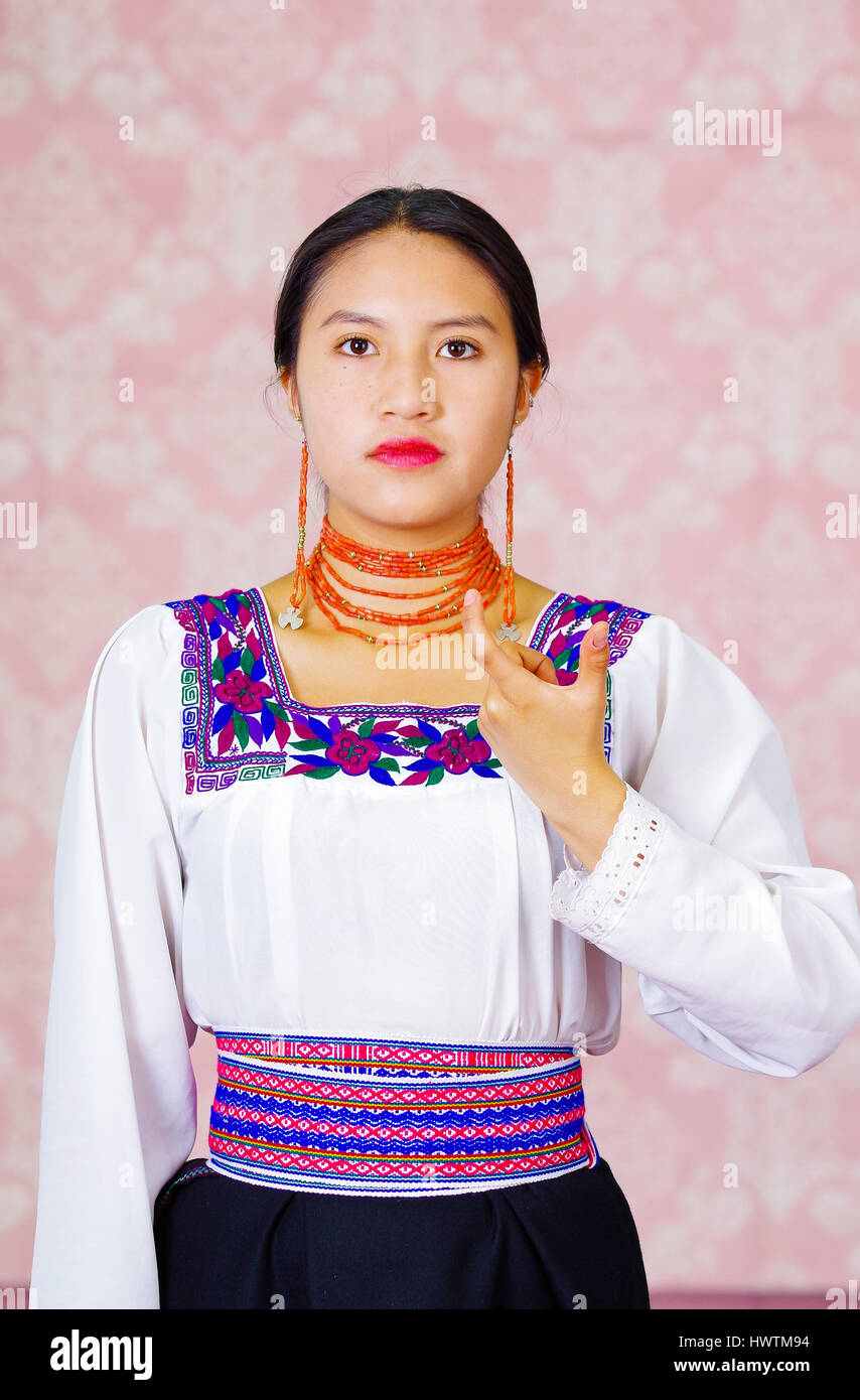Young woman wearing traditional andean dress, facing camera doing sign ...