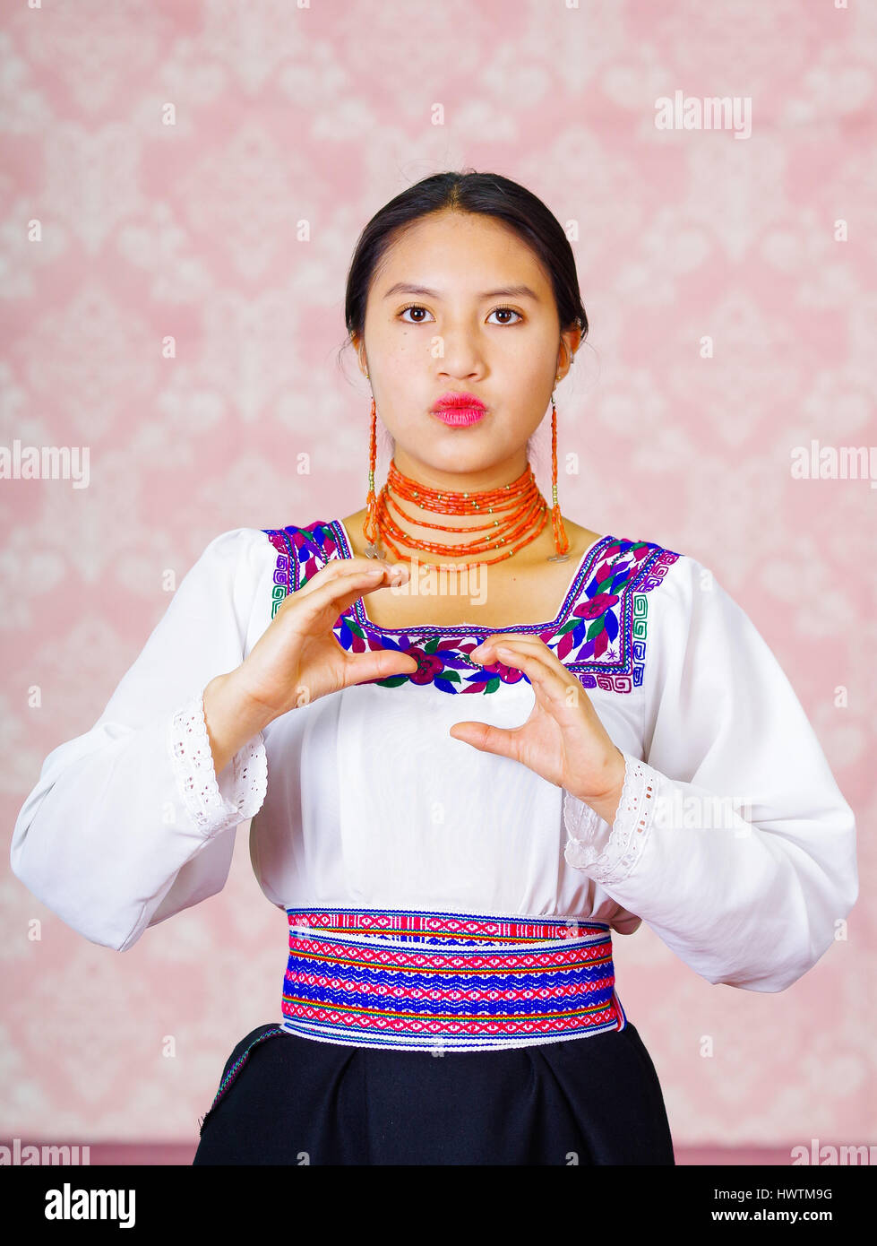 Young woman wearing traditional andean dress, facing camera doing sign ...