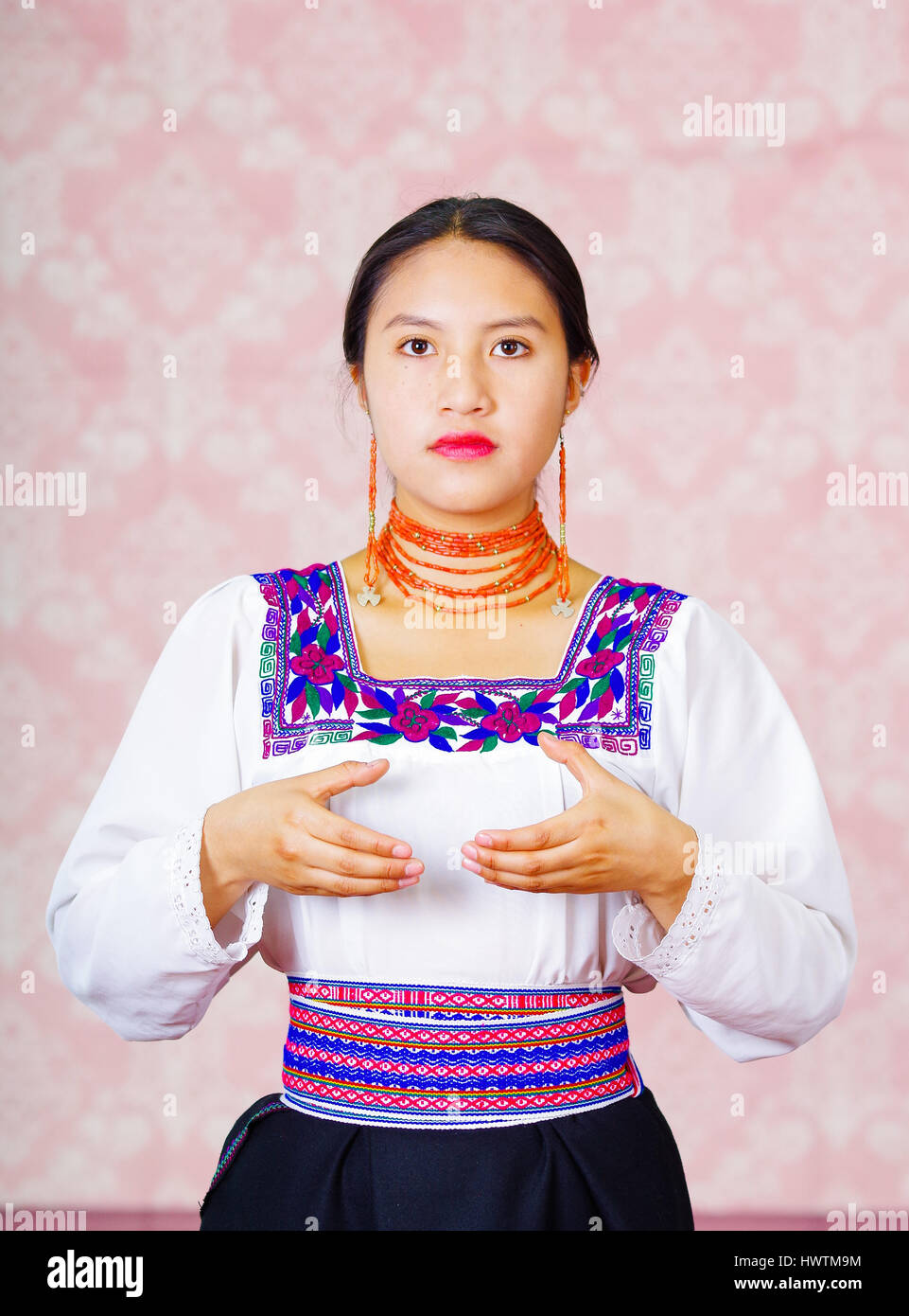 Young woman wearing traditional andean dress, facing camera doing sign ...