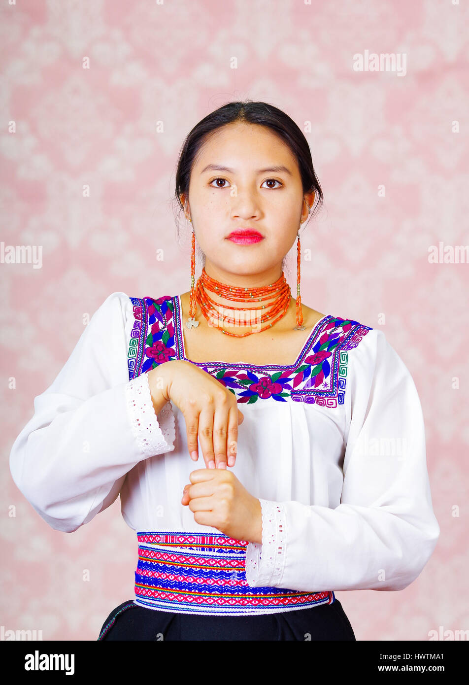 Young woman wearing traditional andean dress, facing camera doing sign ...