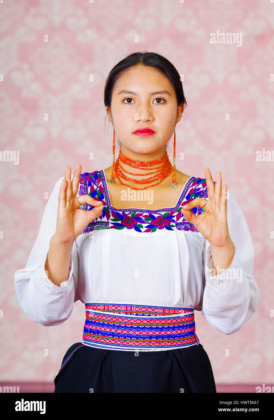 young-woman-wearing-traditional-andean-dress-facing-camera-doing-sign