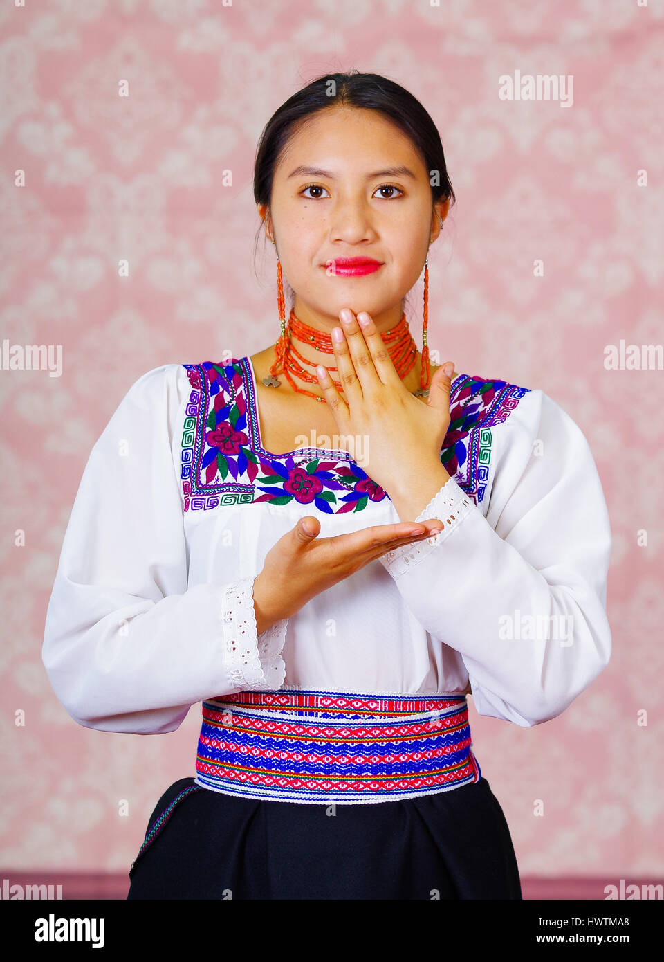 Young woman wearing traditional andean dress, facing camera doing sign ...