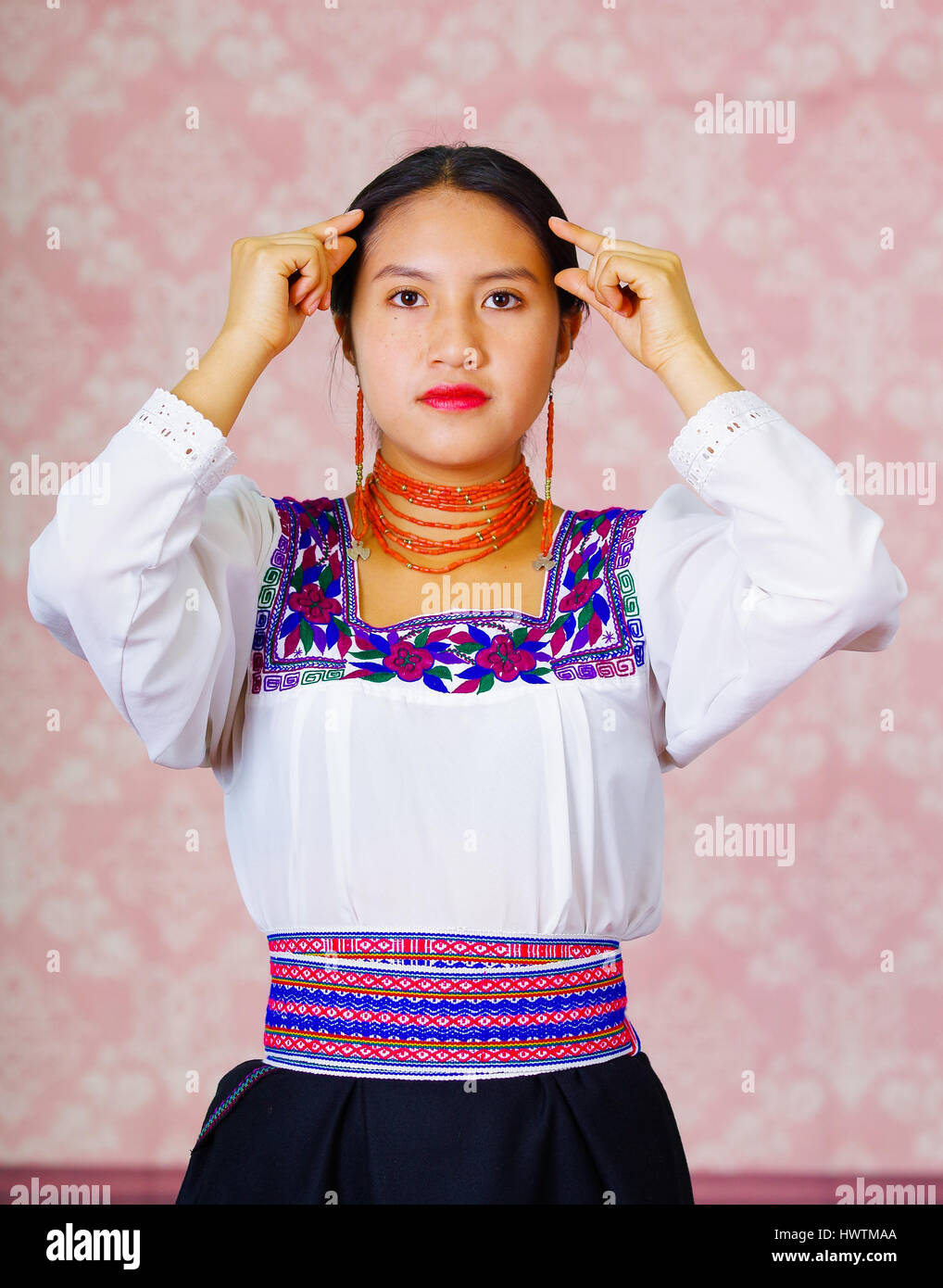 Young woman wearing traditional andean dress, facing camera doing sign ...