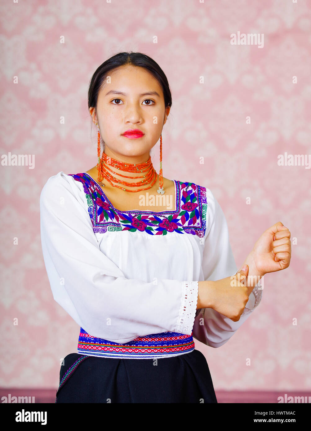 Young woman wearing traditional andean dress, facing camera doing sign ...