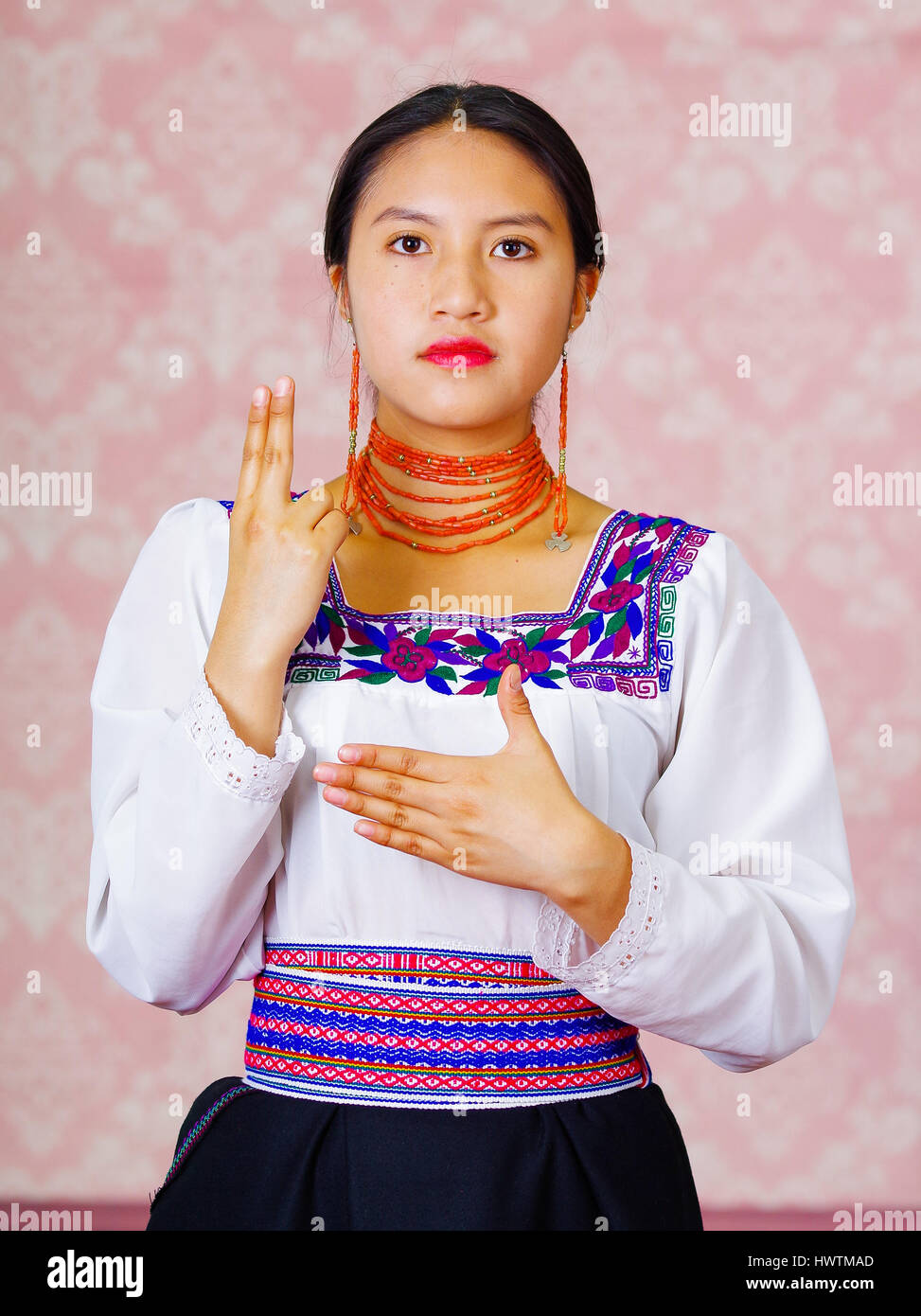 Young Woman Wearing Traditional Andean Dress Facing Camera Doing Sign young-woman-wearing-traditional-andean-dress-facing-camera-doing-sign