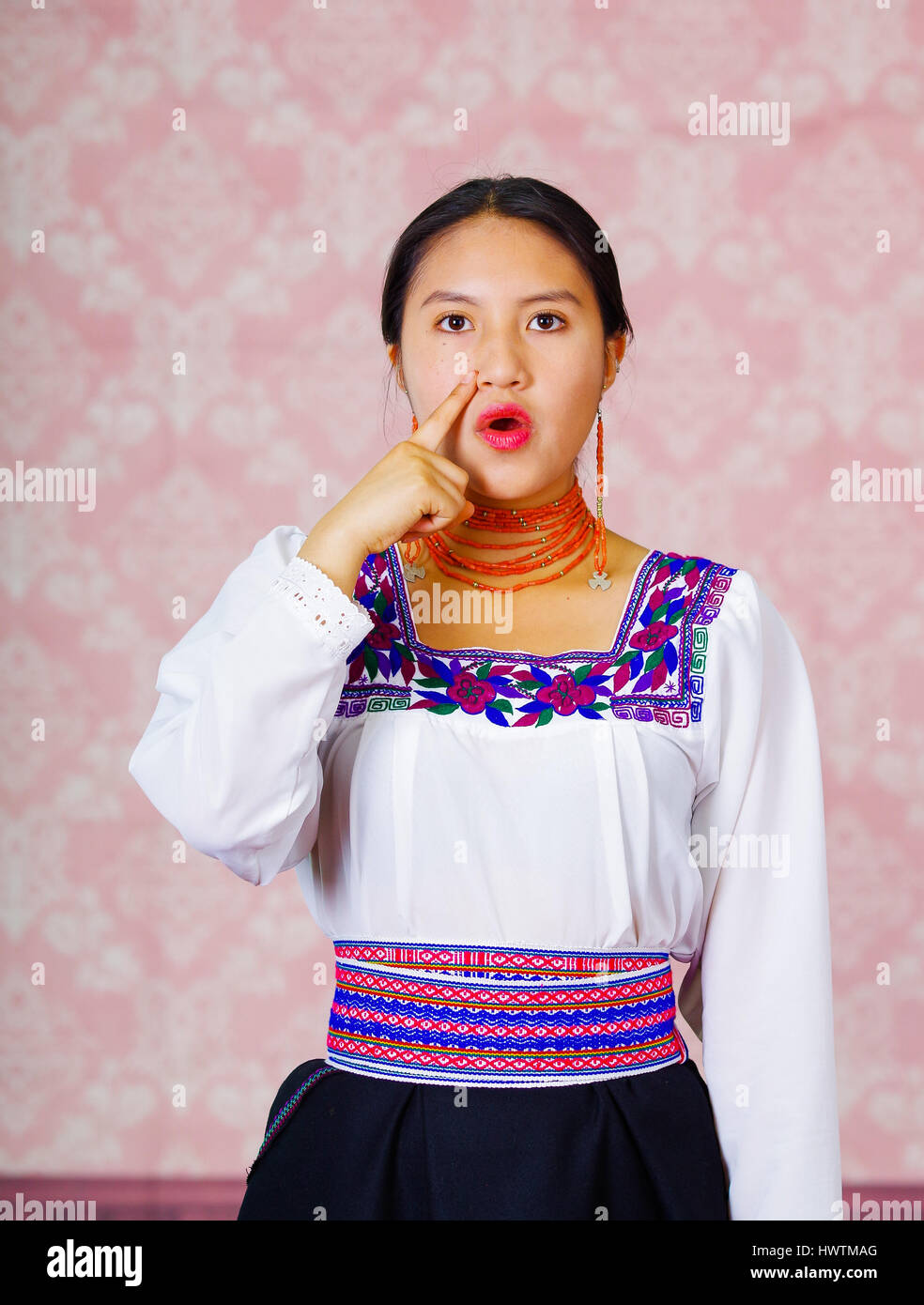 Young woman wearing traditional andean dress, facing camera doing sign ...