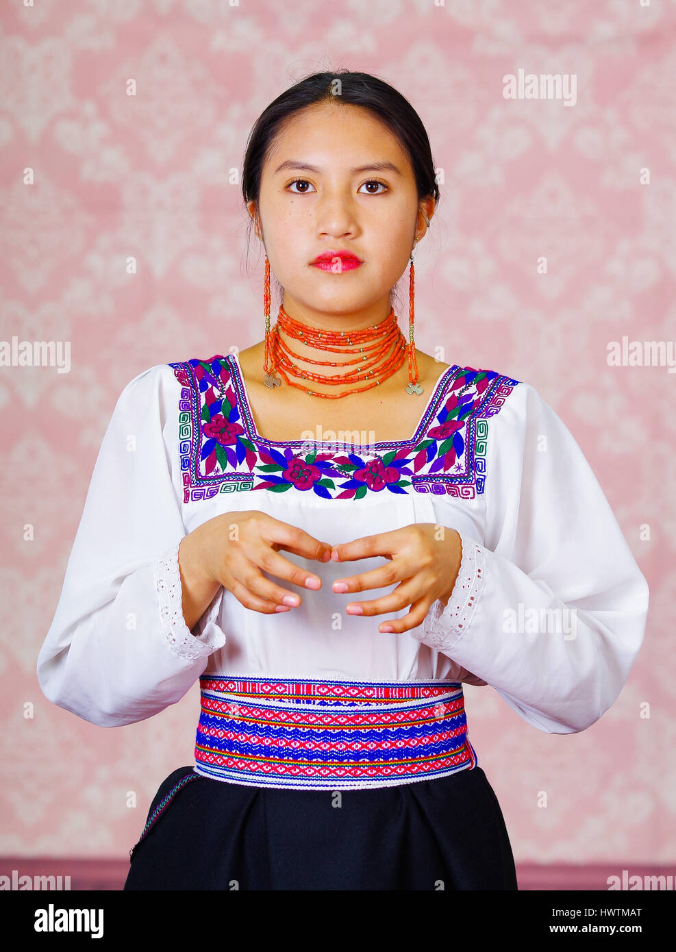 Young woman wearing traditional andean dress, facing camera doing sign ...
