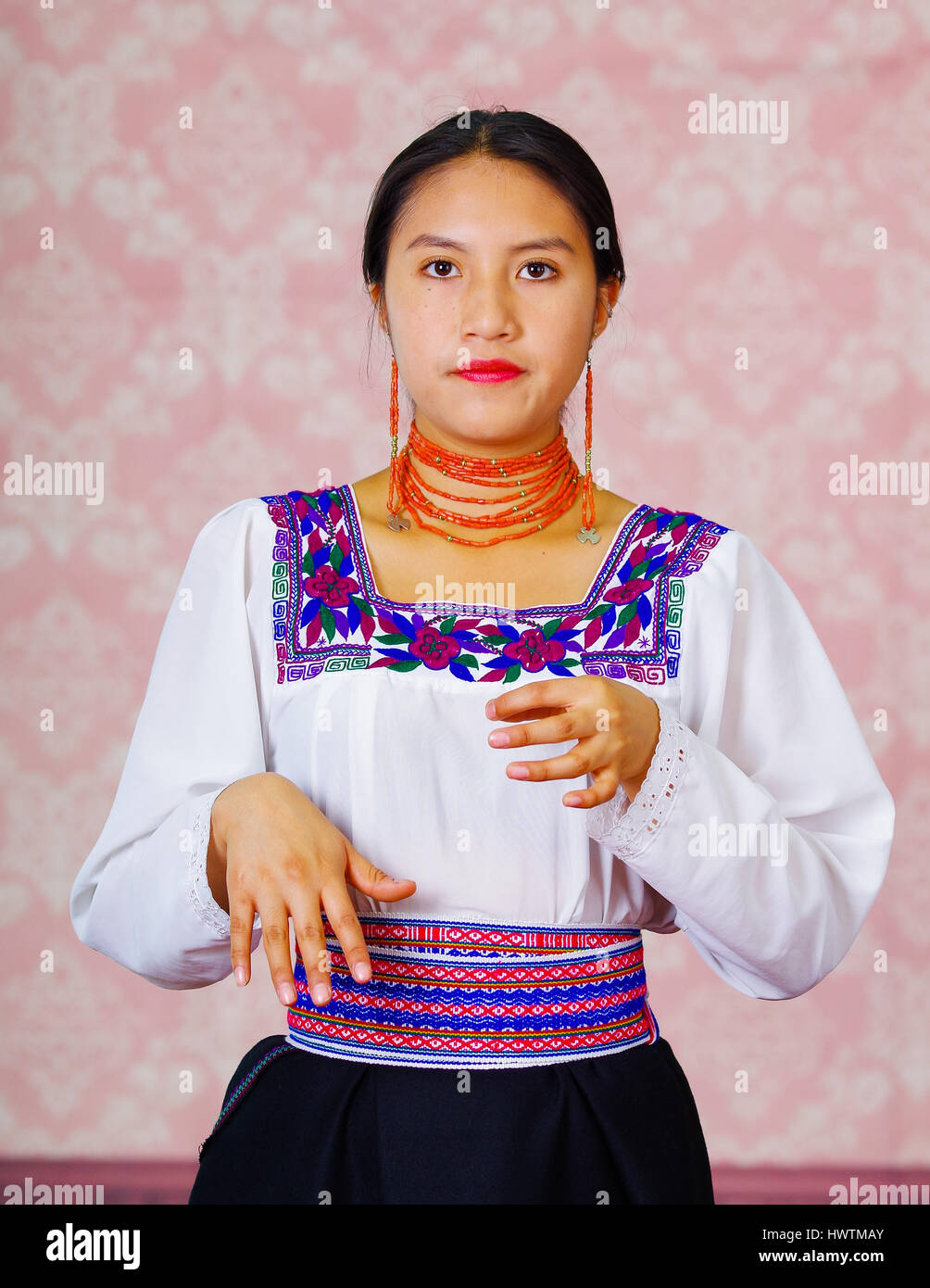 Young woman wearing traditional andean dress, facing camera doing sign ...