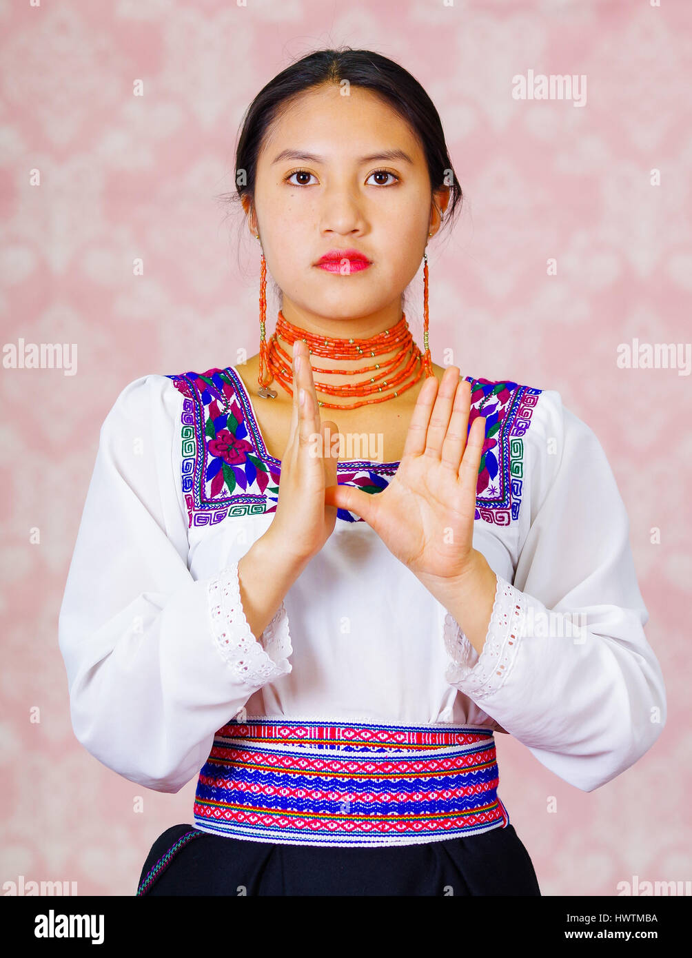 Young woman wearing traditional andean dress, facing camera doing sign ...