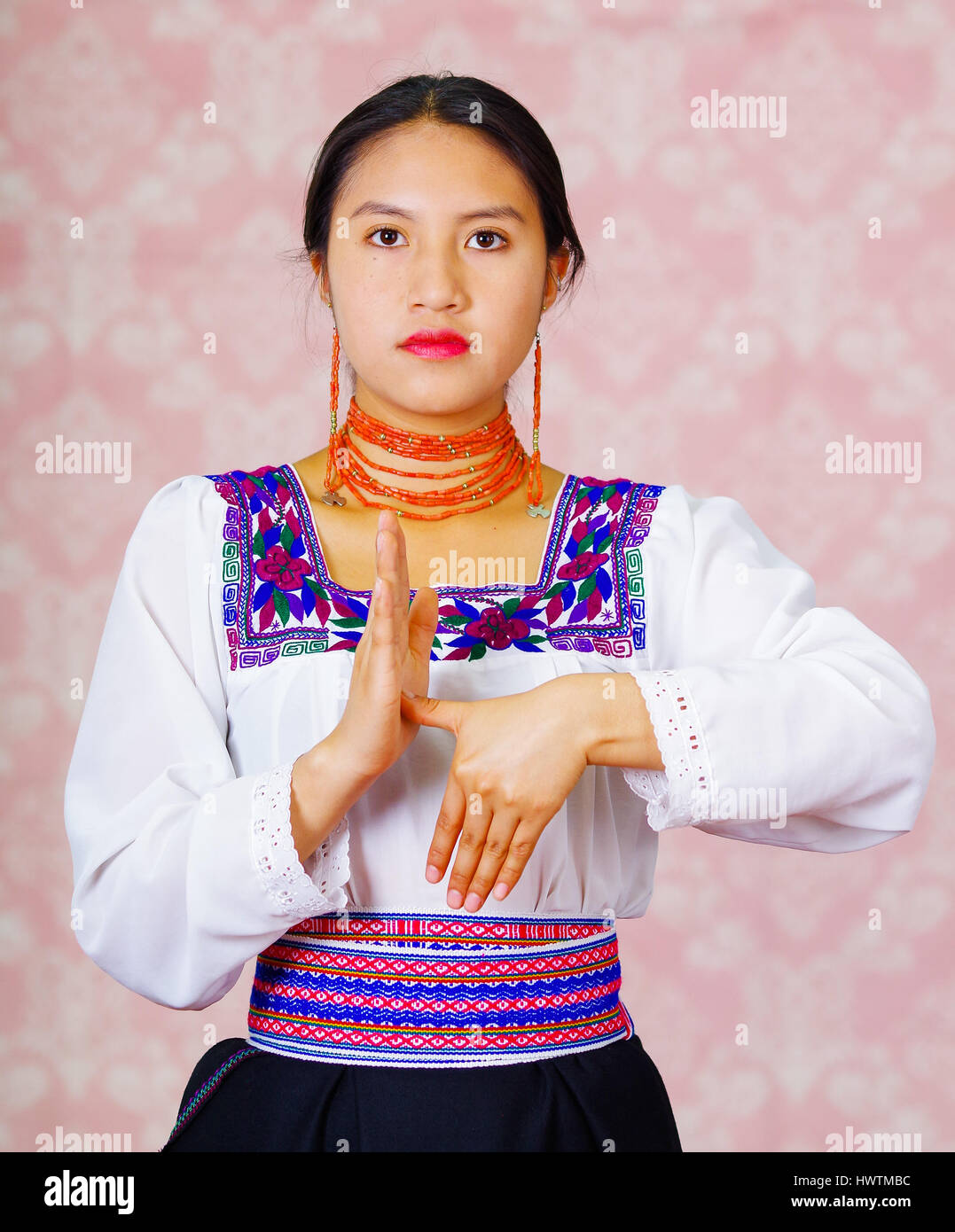 Young woman wearing traditional andean dress, facing camera doing sign ...