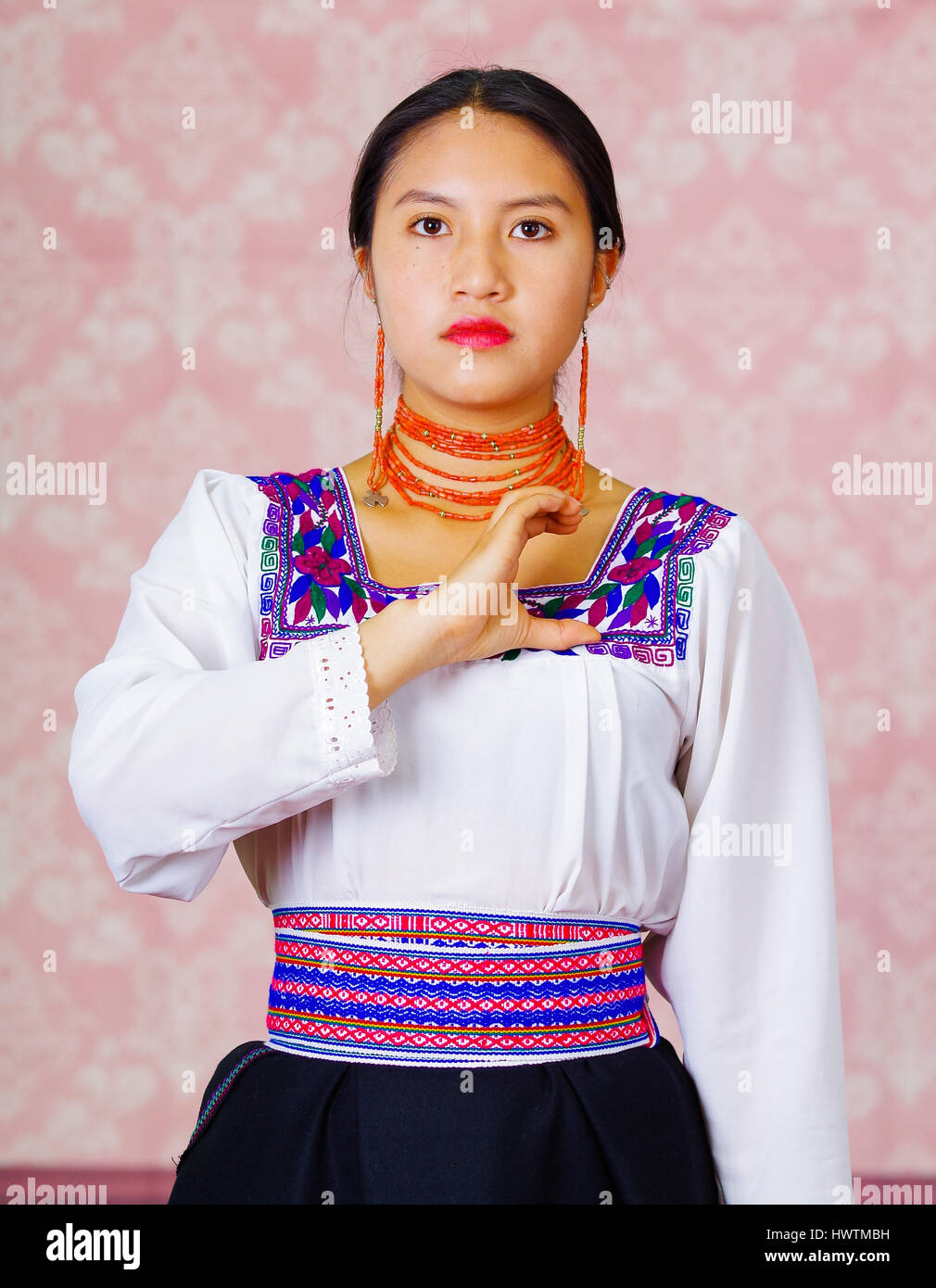 Young woman wearing traditional andean dress, facing camera doing sign ...