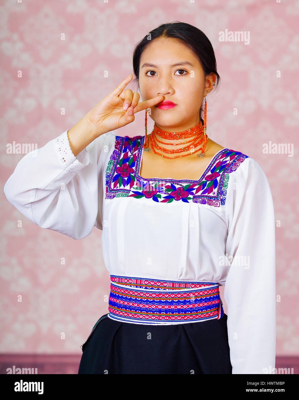 Young woman wearing traditional andean dress, facing camera doing sign ...