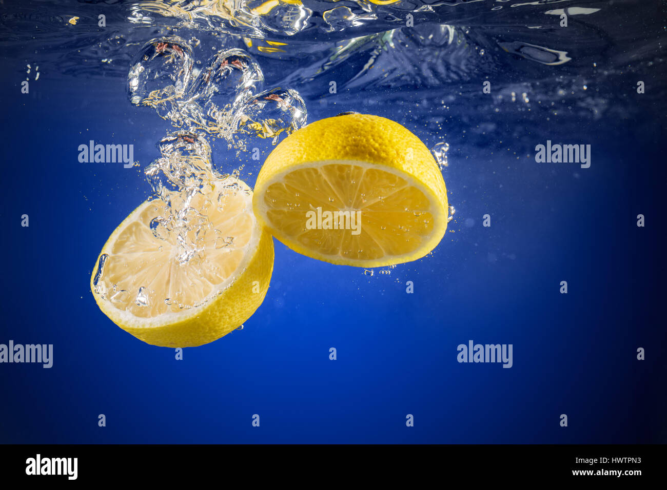 Fresh lemon dropped into water background Stock Photo - Alamy