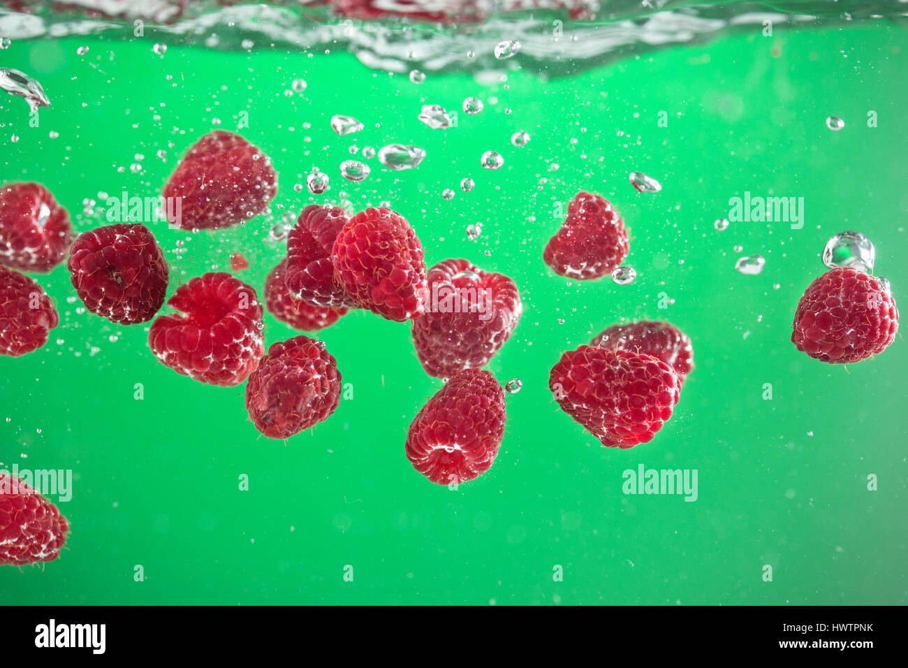 raspberry dropped in water tank background Stock Photo - Alamy
