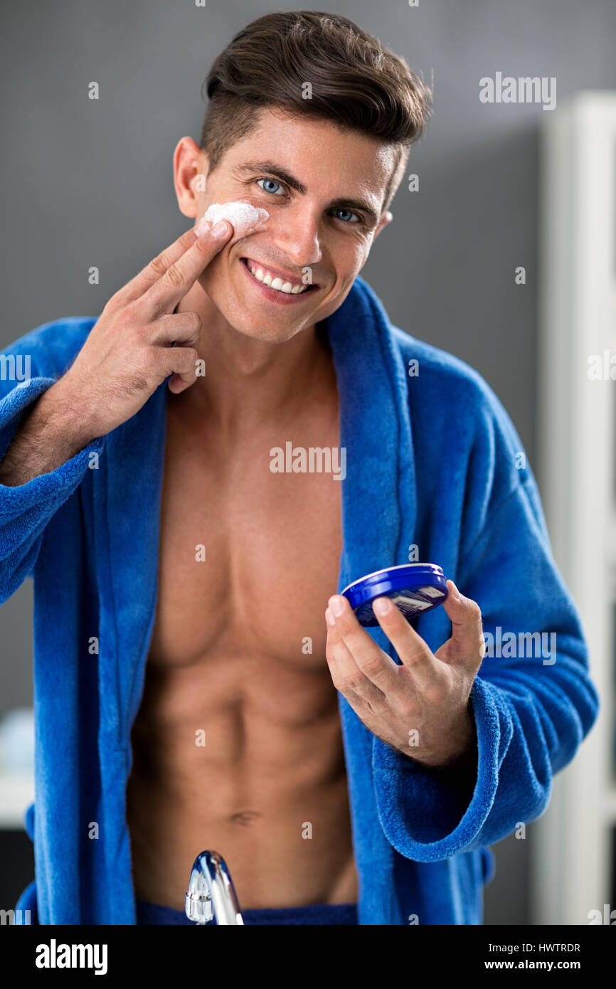 Handsome man applying facial cream over gray background Stock Photo - Alamy