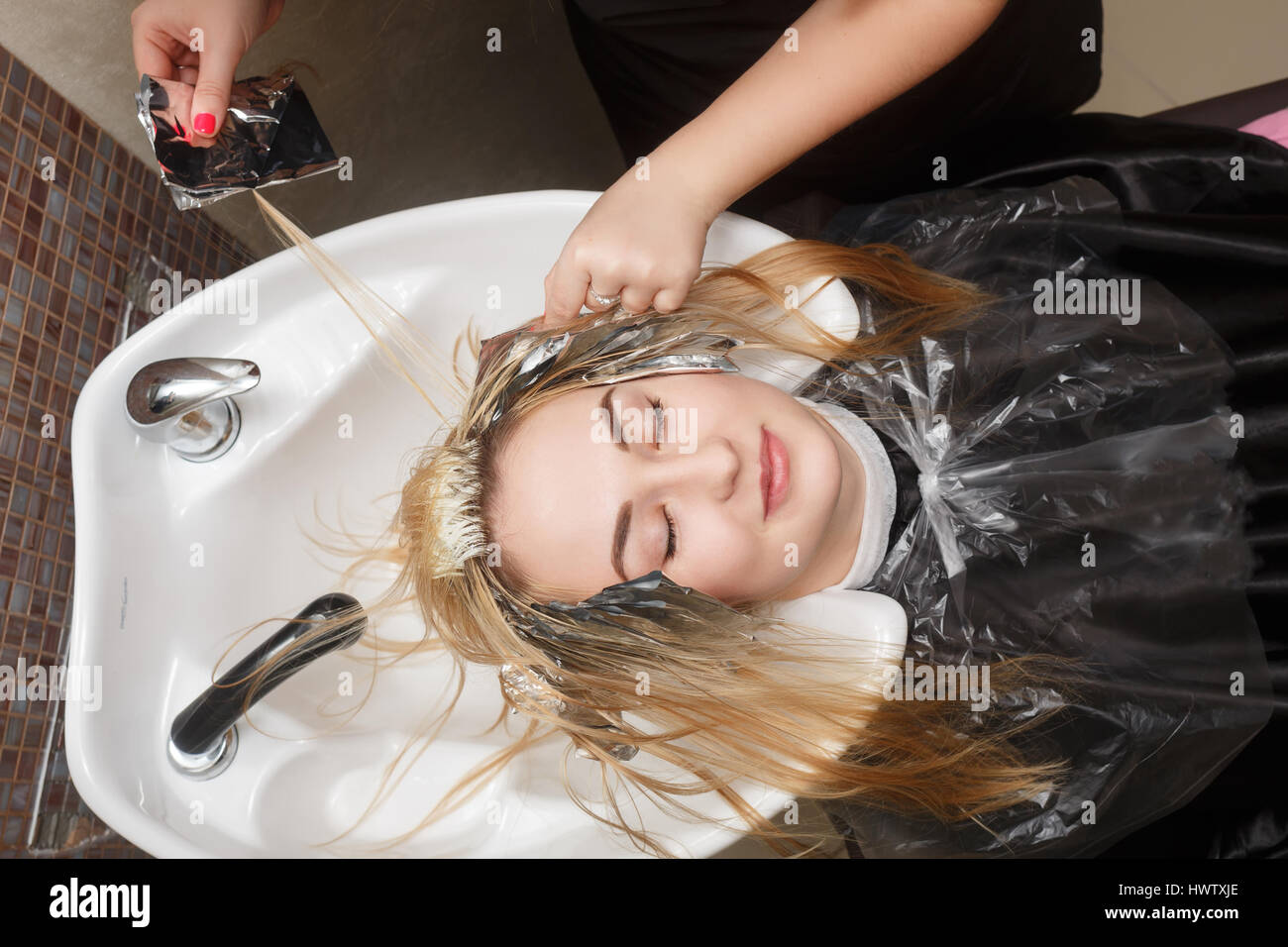 Professional hairdresser washes client's head after hair coloring ...