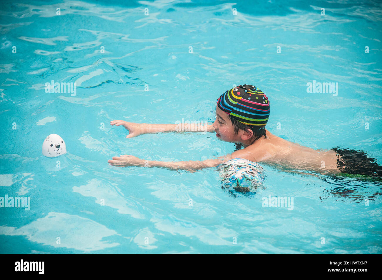 A young boy in a clear water swimming poop playing with a toy Stock ...