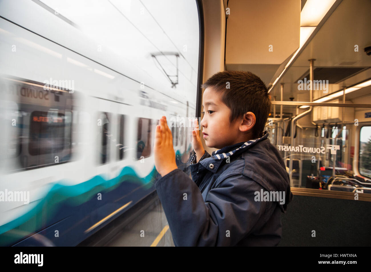 A little boy looking out of a train window at a blurred passing train ...