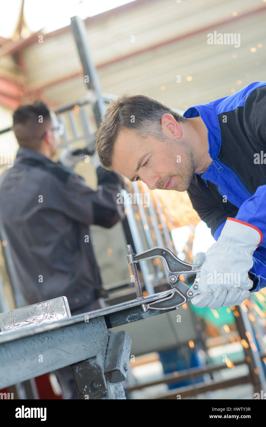 Workman clamping metal onto bench Stock Photo - Alamy