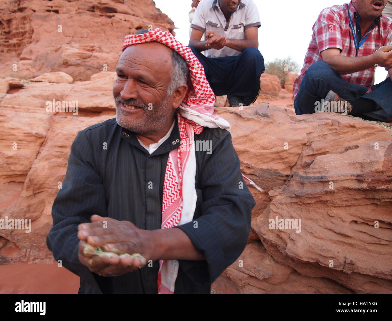 Man of bedouin tribe, dressed in costume, is presenting tourists how to ...