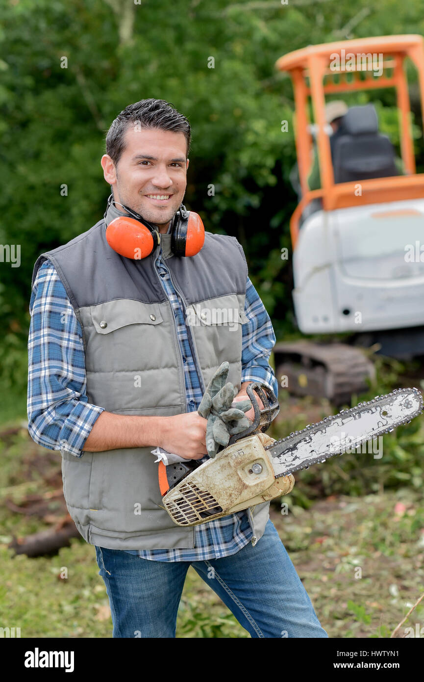 Man holding chainsaw, wearing ear protectors Stock Photo - Alamy