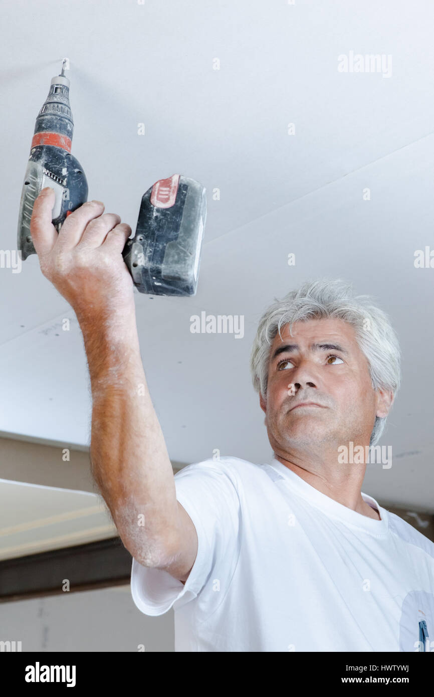 Builder drilling hole in ceiling Stock Photo - Alamy