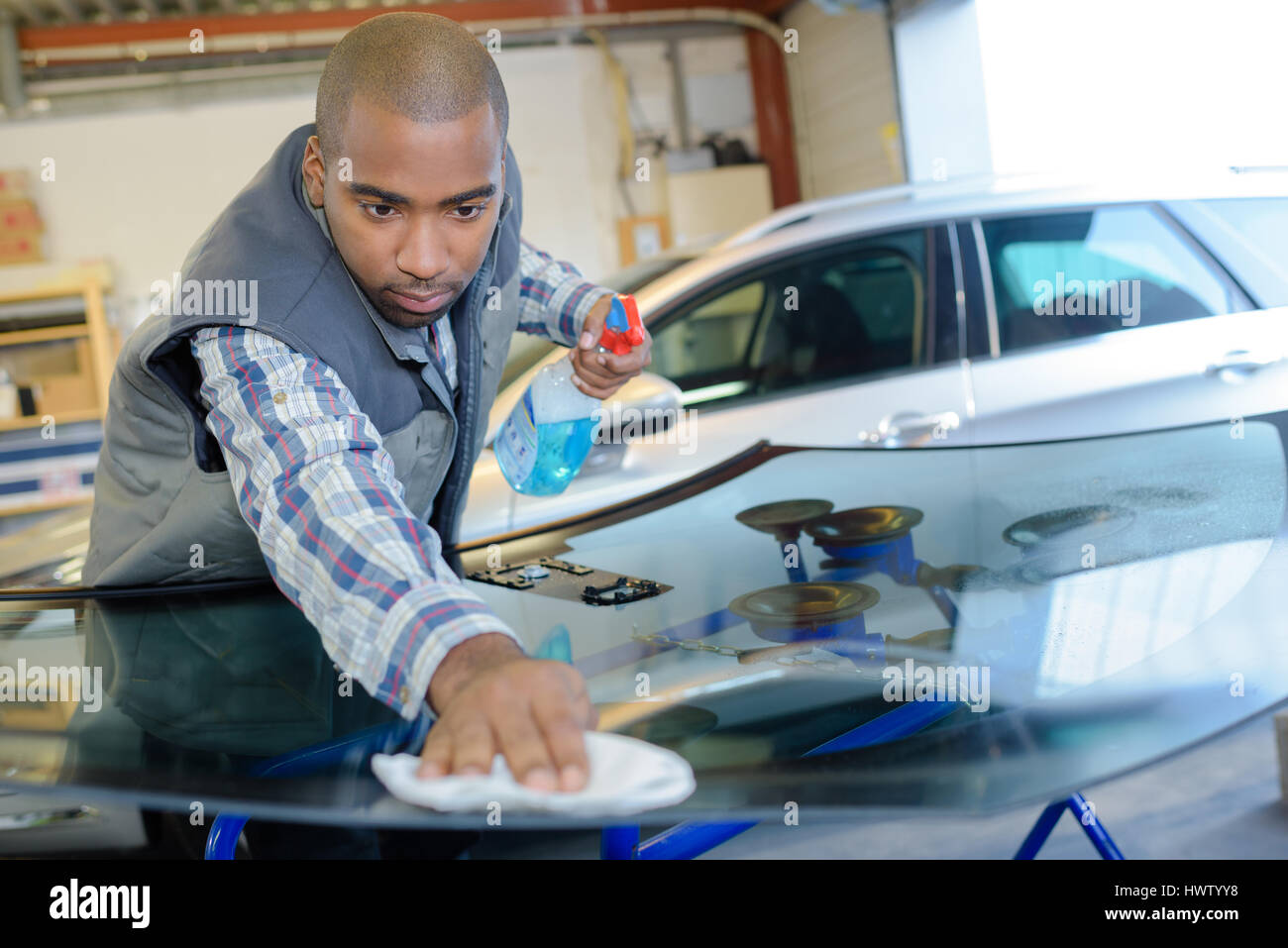 Garage worker polishing replacement windscreen Stock Photo - Alamy