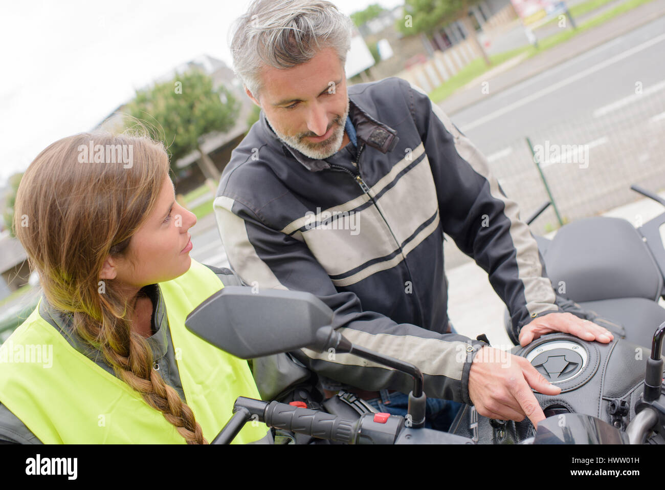 Instructor explaining motorcycle to lady Stock Photo - Alamy