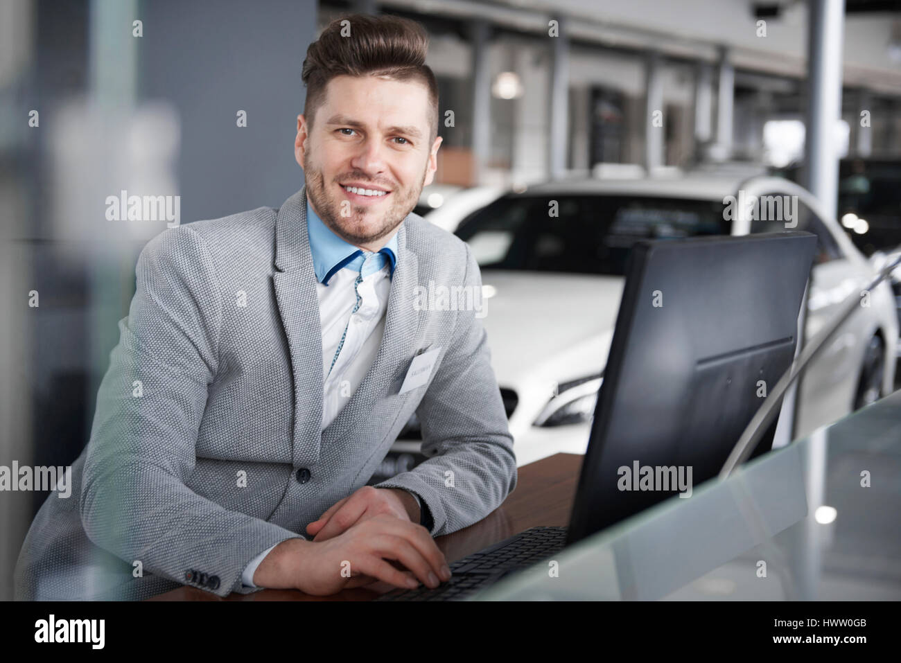 Portrait of salesman leaning at computer desk Stock Photo - Alamy