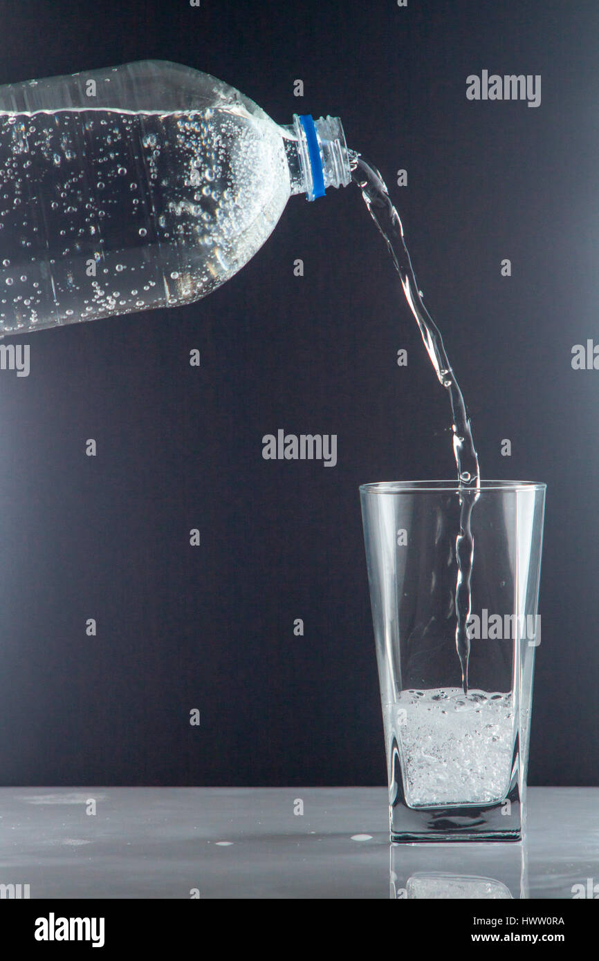 Pure mineral water pouring from a bottle into a glass. bottle of clear drinking cold mineral ...