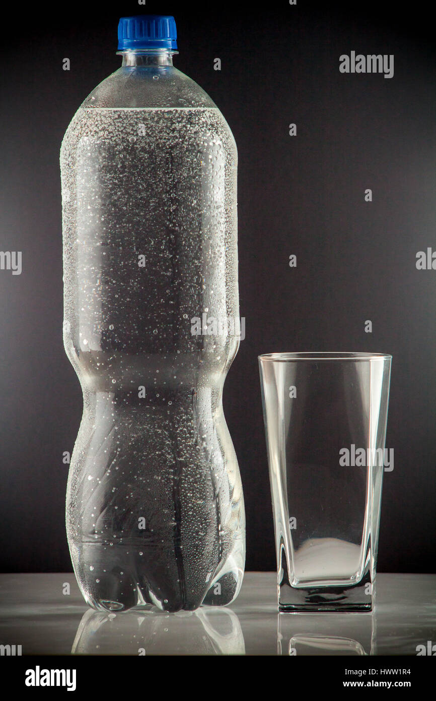 Pure mineral water pouring from a bottle into a glass. bottle of clear drinking cold mineral ...