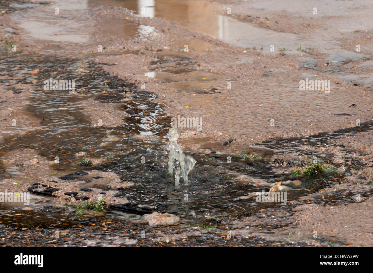 water damage to road from burst leaking water pipe Stock Photo - Alamy