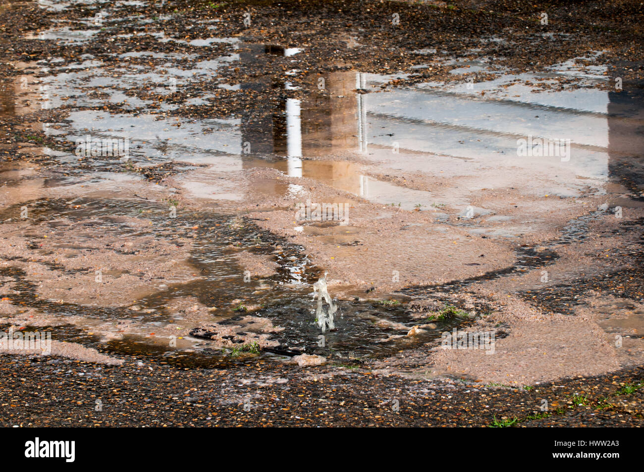 water damage to road from burst leaking water pipe Stock Photo - Alamy